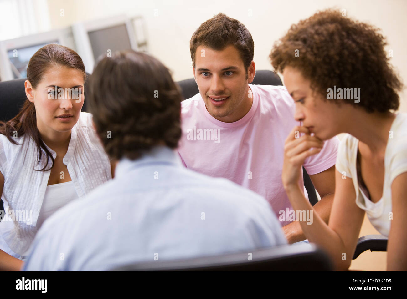 Man giving lecture to three people in computer room Stock Photo - Alamy
