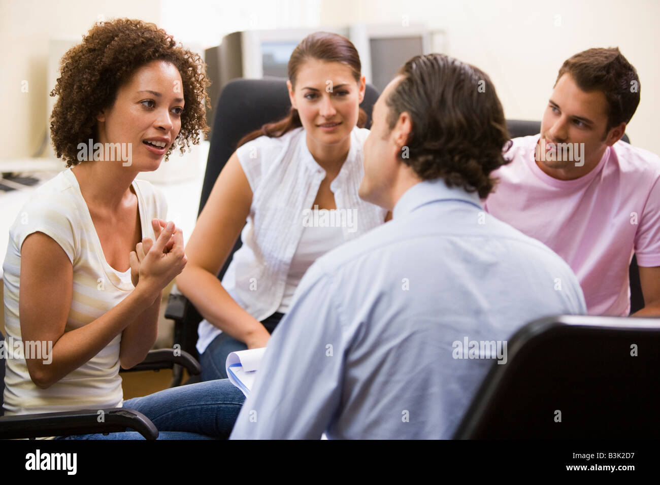 Man giving lecture to three people in computer room Stock Photo - Alamy