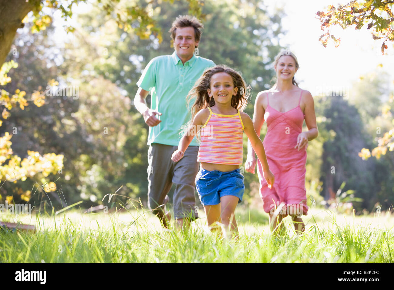 Family running outdoors smiling Stock Photo - Alamy