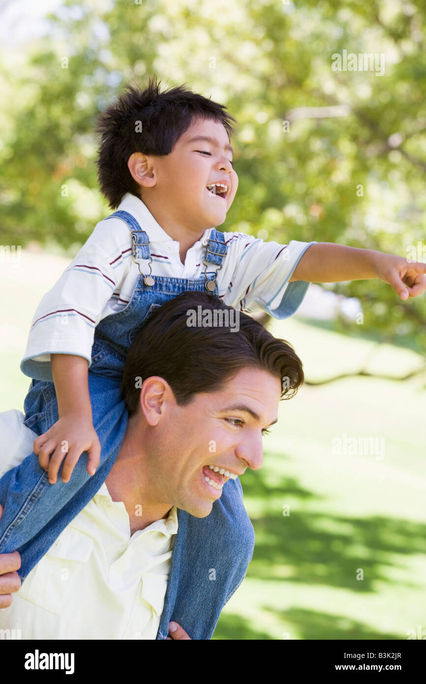 Man giving young boy shoulder ride outdoors smiling Stock Photo - Alamy