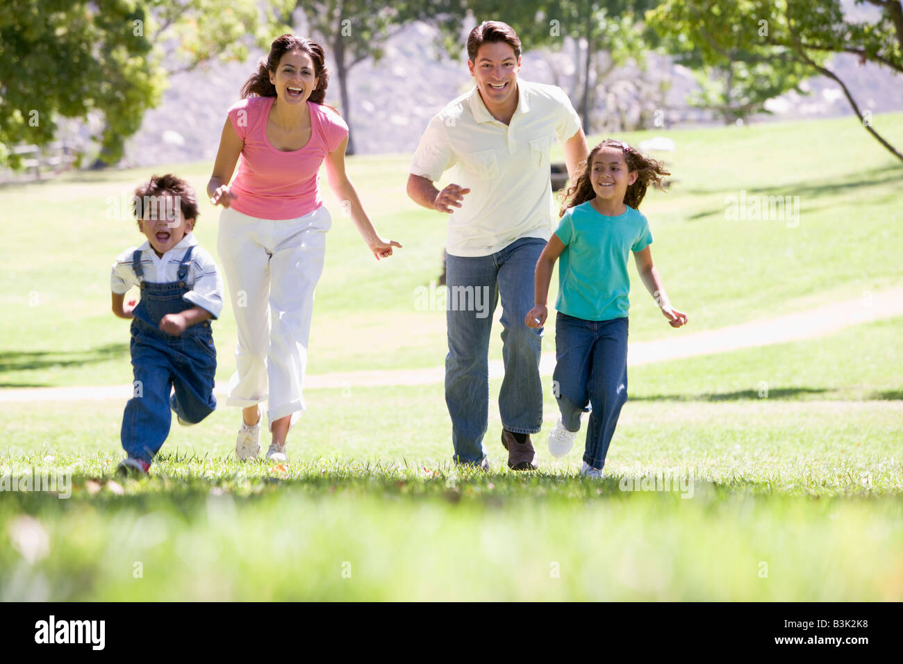 Family running outdoors smiling Stock Photo - Alamy