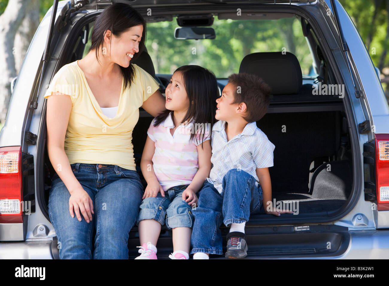 Woman with two children sitting in back of van smiling Stock Photo - Alamy