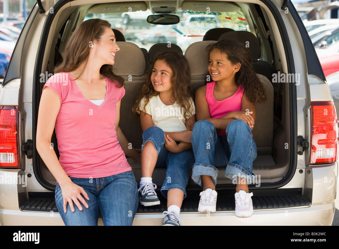 Woman with two young girls sitting in back of van smiling Stock Photo ...