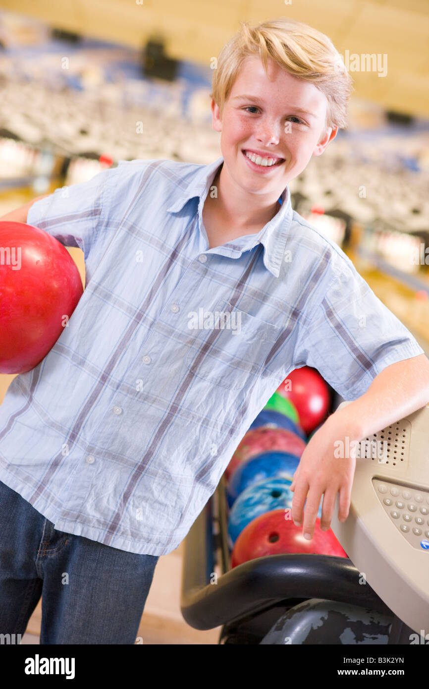 Young boy in bowling alley holding ball and smiling Stock Photo - Alamy