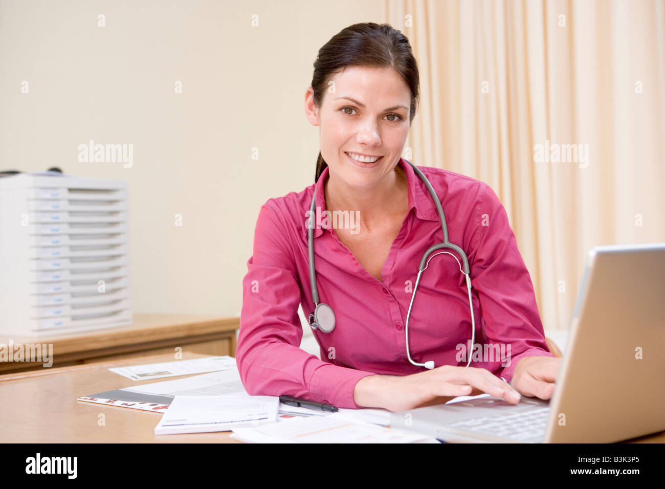 Doctor using laptop in doctor's office smiling Stock Photo - Alamy