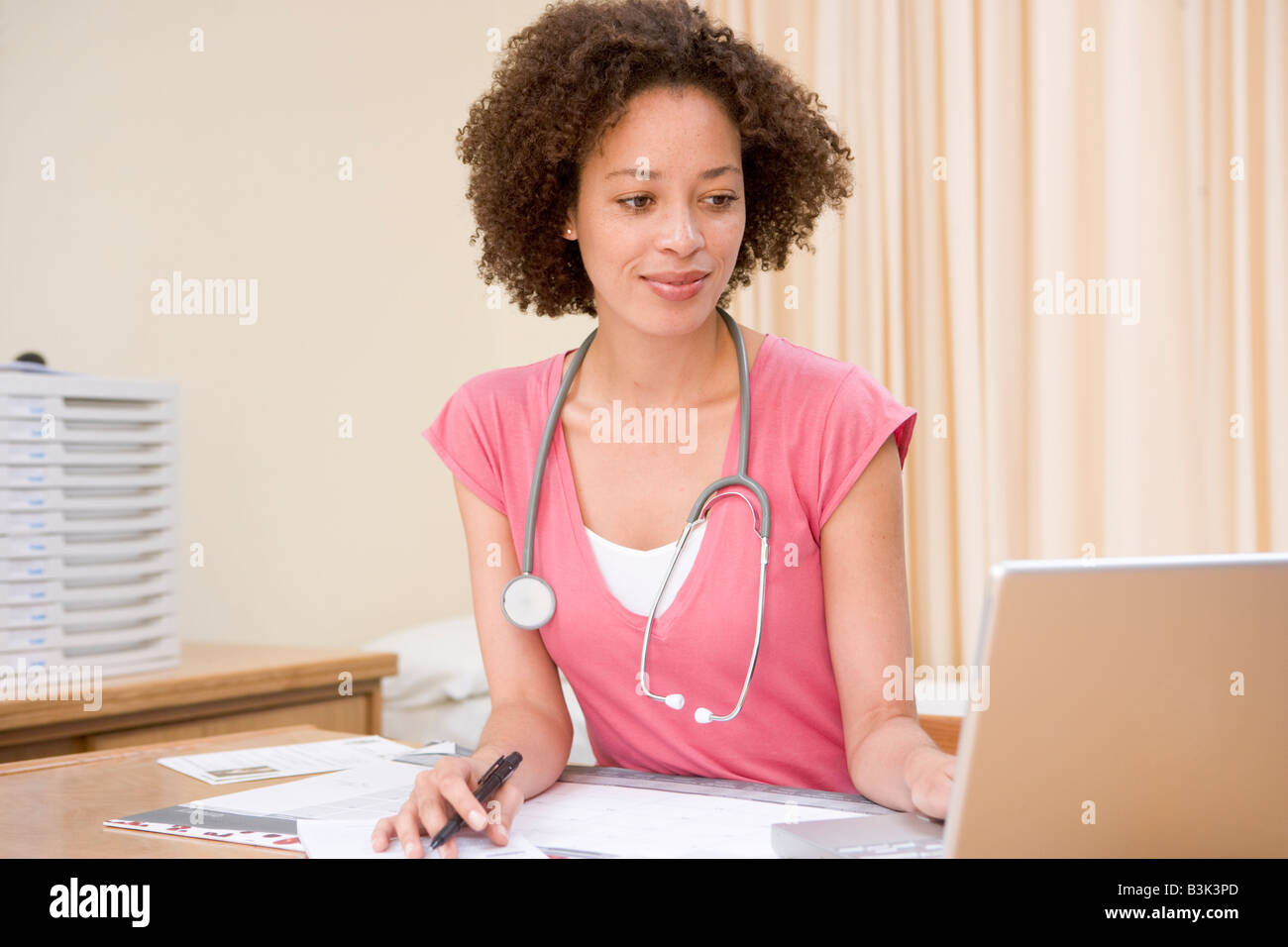 Doctor using laptop in doctor's office smiling Stock Photo - Alamy