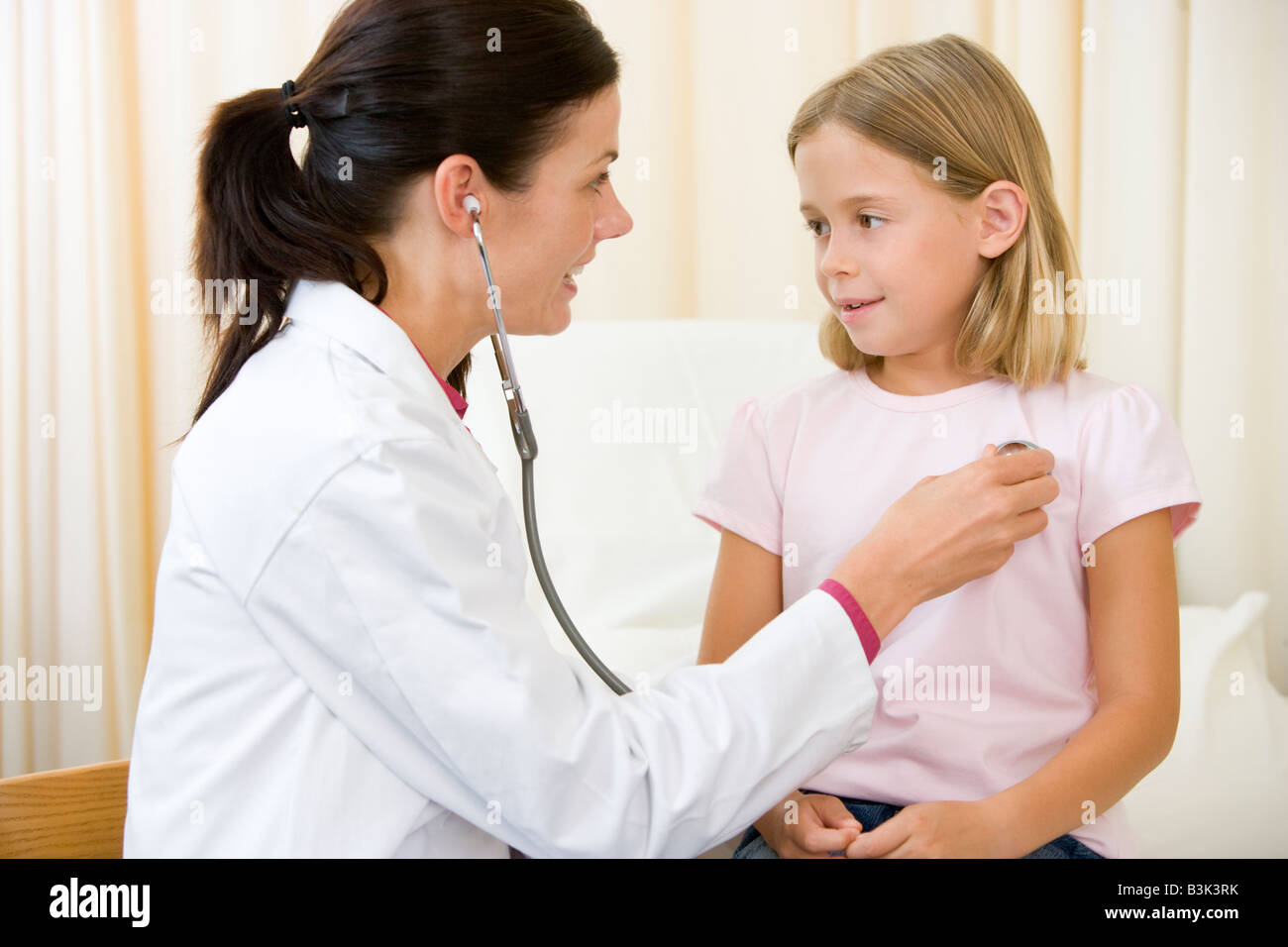 Doctor Giving Checkup With Stethoscope To Young Girl In Exam Room Stock