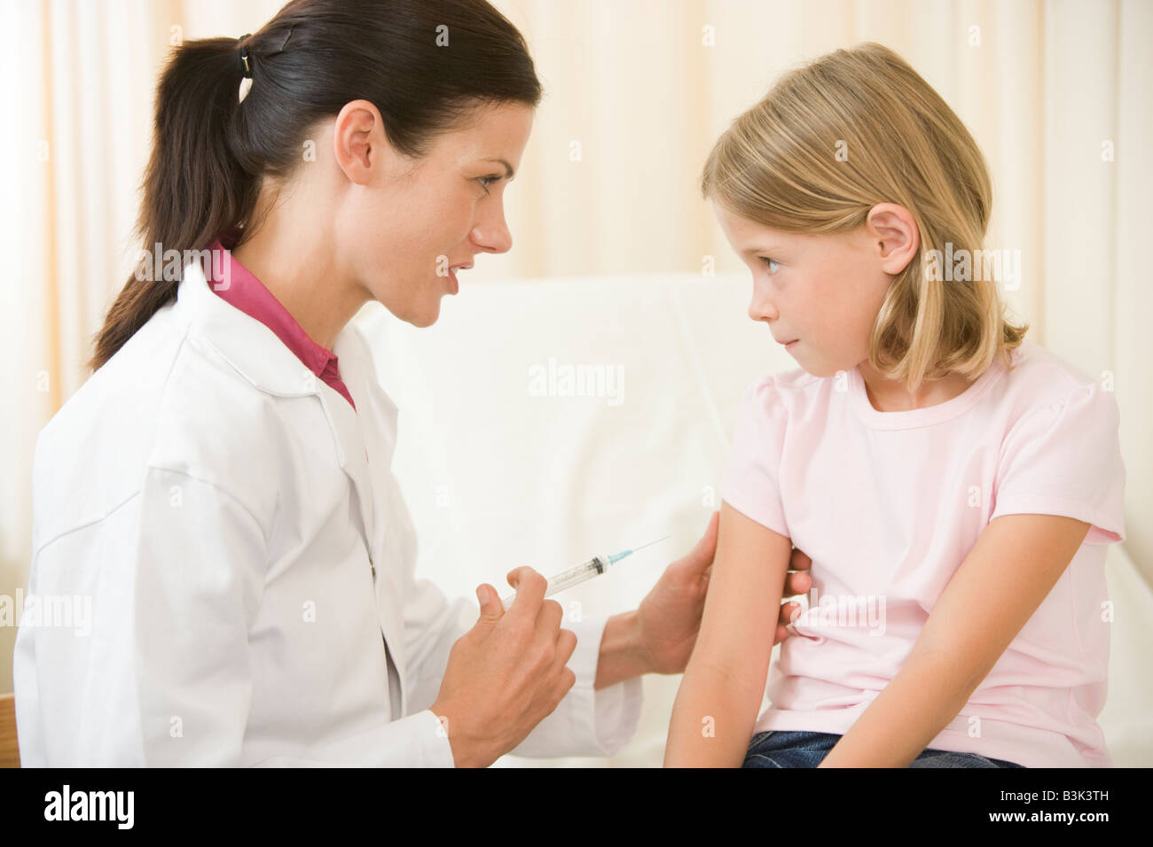 Doctor giving needle to young girl in exam room Stock Photo - Alamy