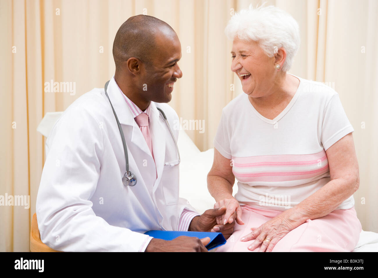 Doctor giving checkup to woman in exam room smiling Stock Photo - Alamy