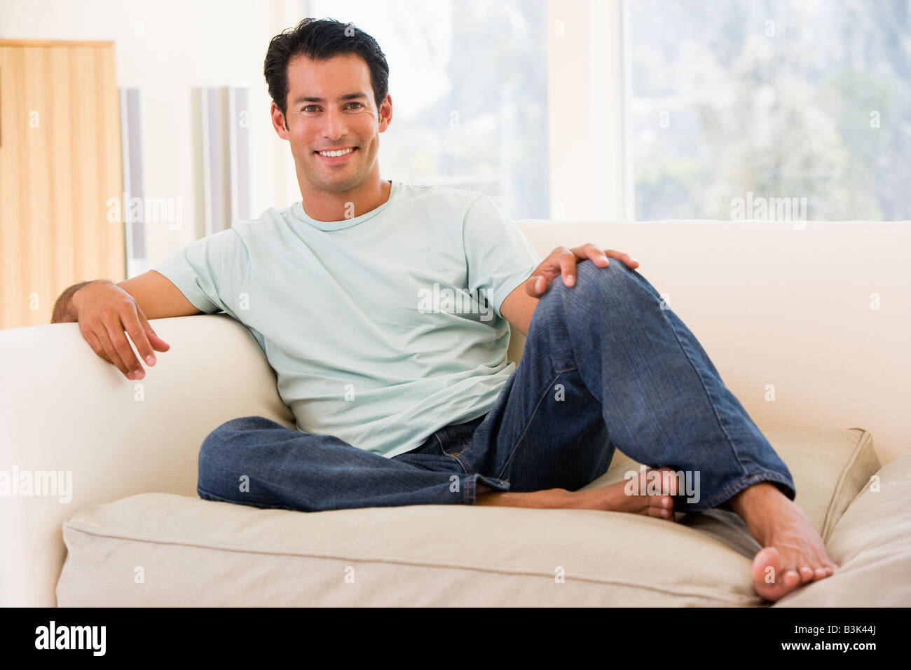 Man sitting in living room smiling Stock Photo - Alamy