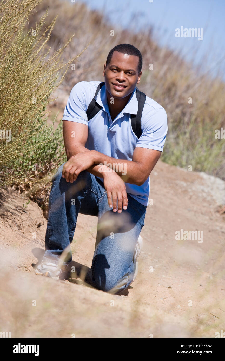 Man crouching on path to beach smiling Stock Photo - Alamy