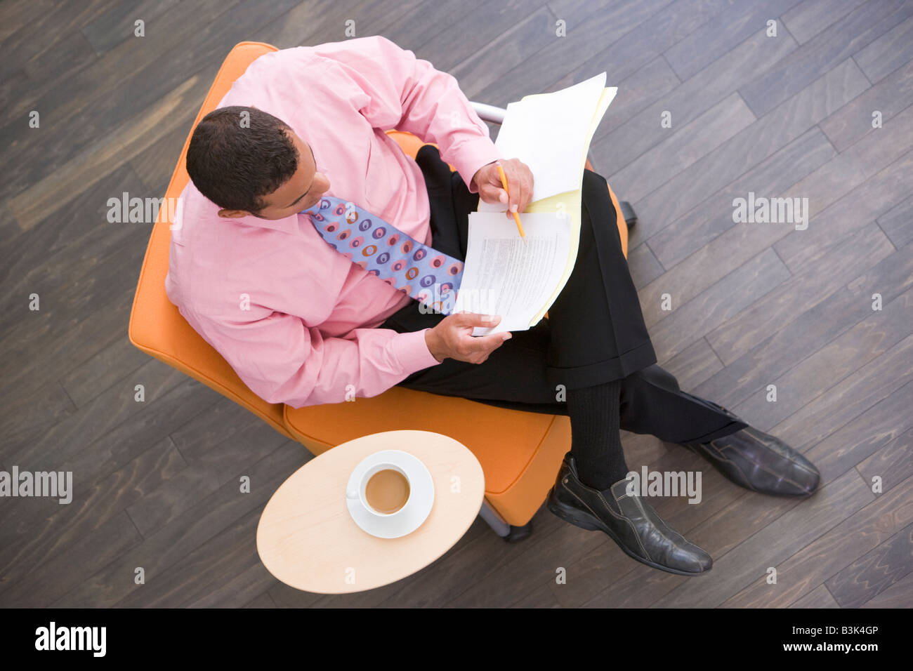 Businessman sitting indoors with coffee and folder Stock Photo - Alamy