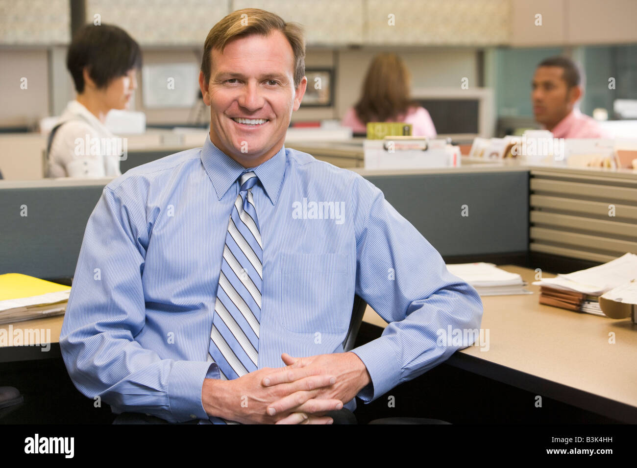 Businessman in cubicle smiling Stock Photo - Alamy