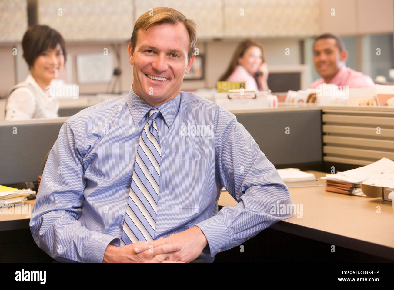 Businessman in cubicle smiling Stock Photo - Alamy