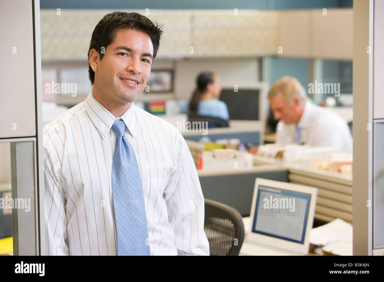 Businessman standing in cubicle smiling Stock Photo - Alamy