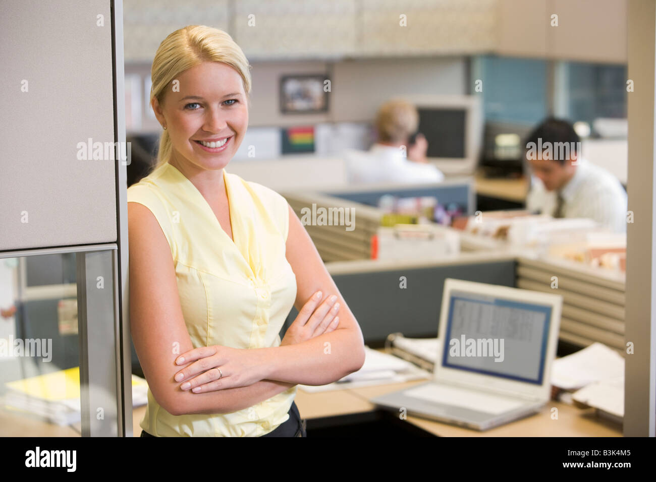 Businesswoman standing in cubicle smiling Stock Photo - Alamy