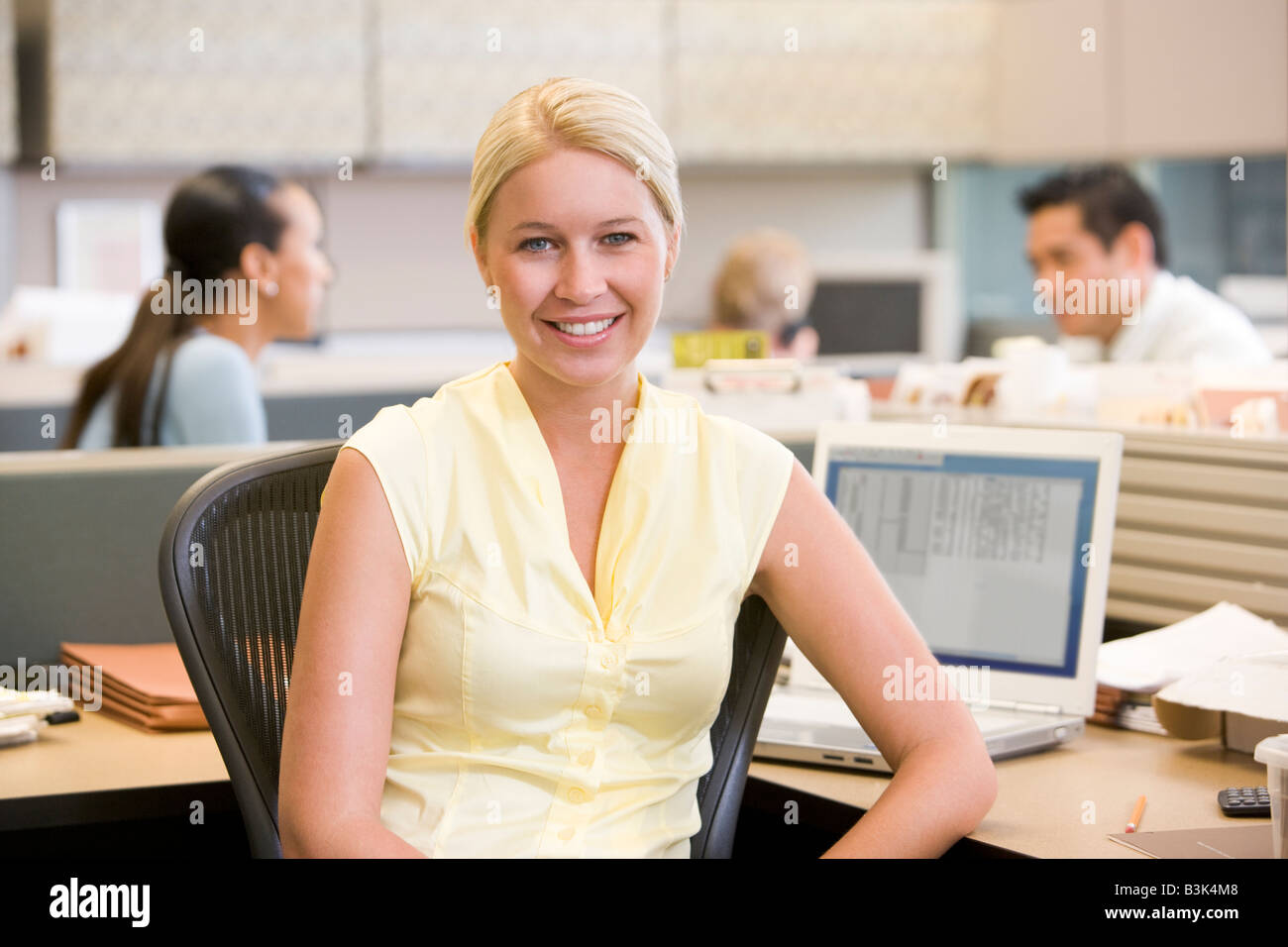 Businesswoman in cubicle smiling Stock Photo - Alamy