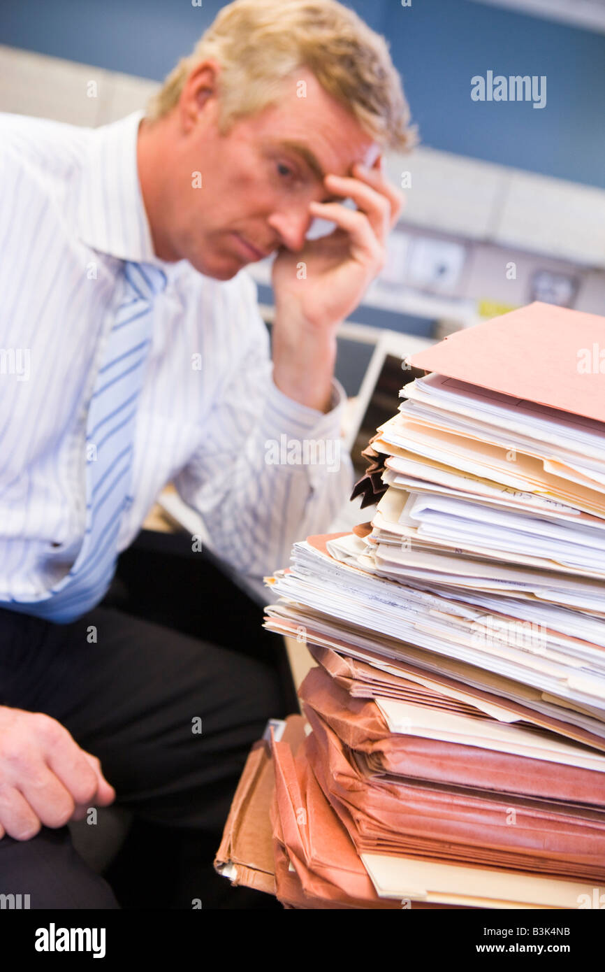 Businessman in cubicle with laptop and stacks of files Stock Photo - Alamy