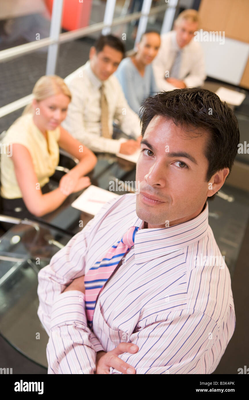 Businessman with four businesspeople at boardroom table in background ...