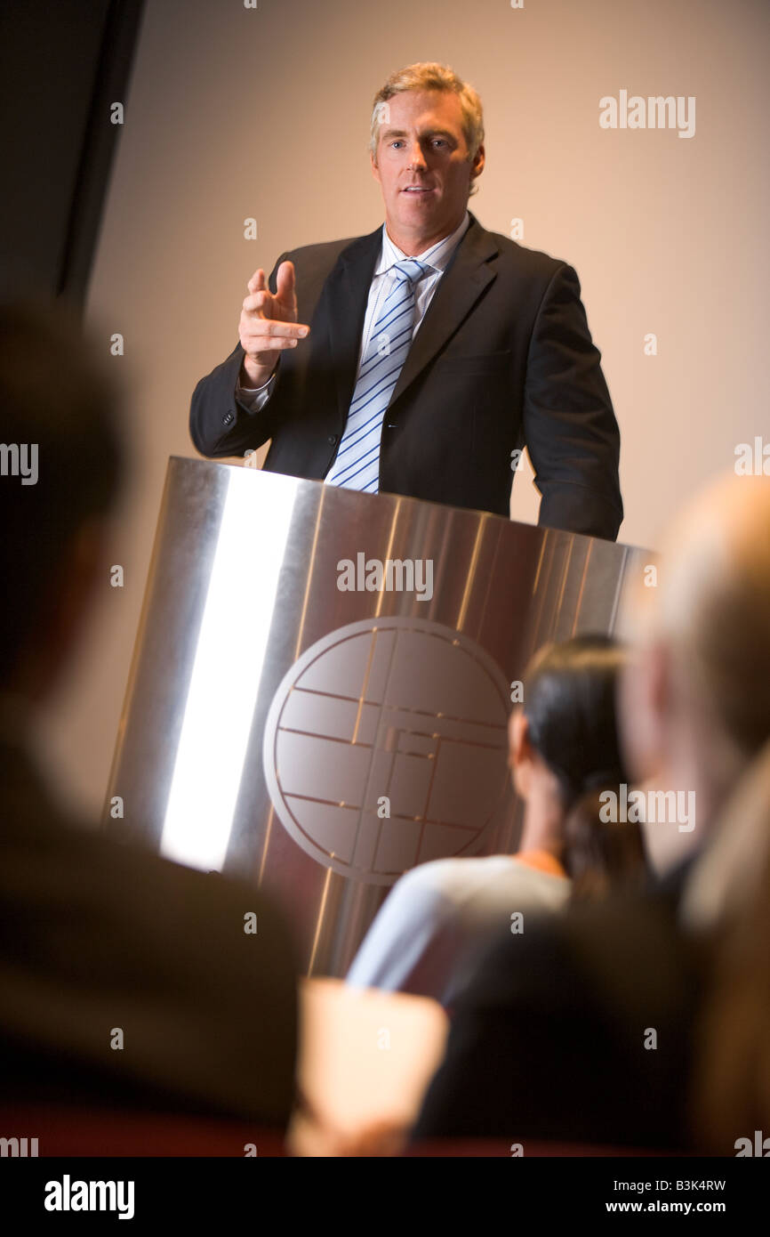 Businessman giving presentation at podium Stock Photo - Alamy