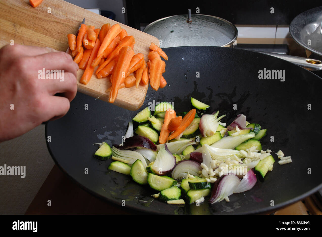 Putting carrots in a frying pan Stock Photo - Alamy