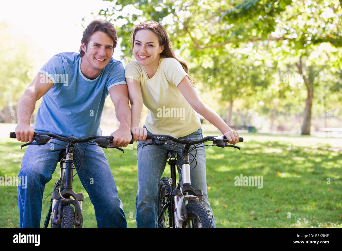 Couple on bikes outdoors smiling Stock Photo - Alamy