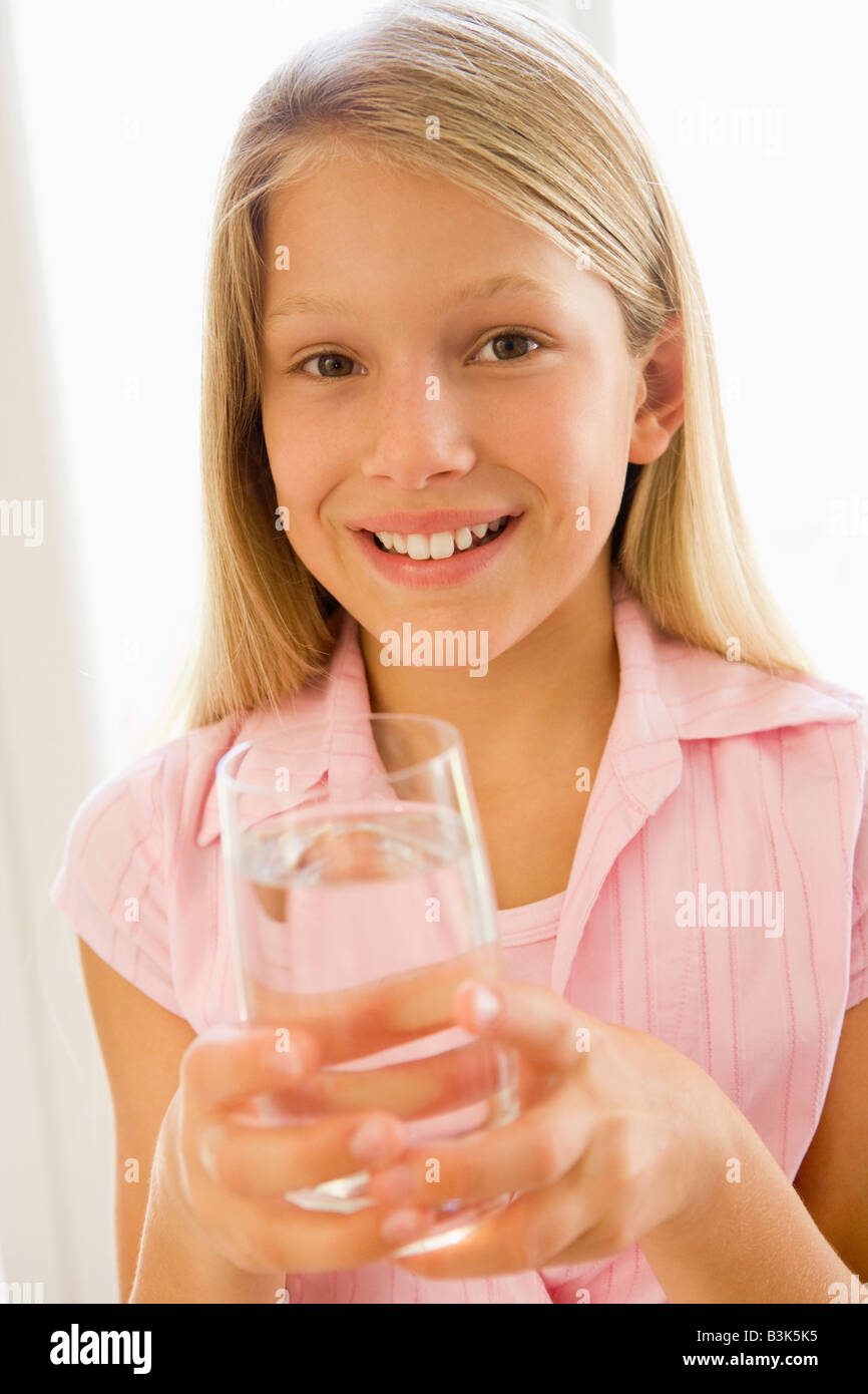 Young girl indoors drinking water smiling Stock Photo - Alamy