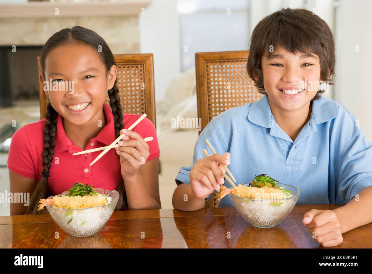 Two young children eating Chinese food in dining room smiling Stock ...