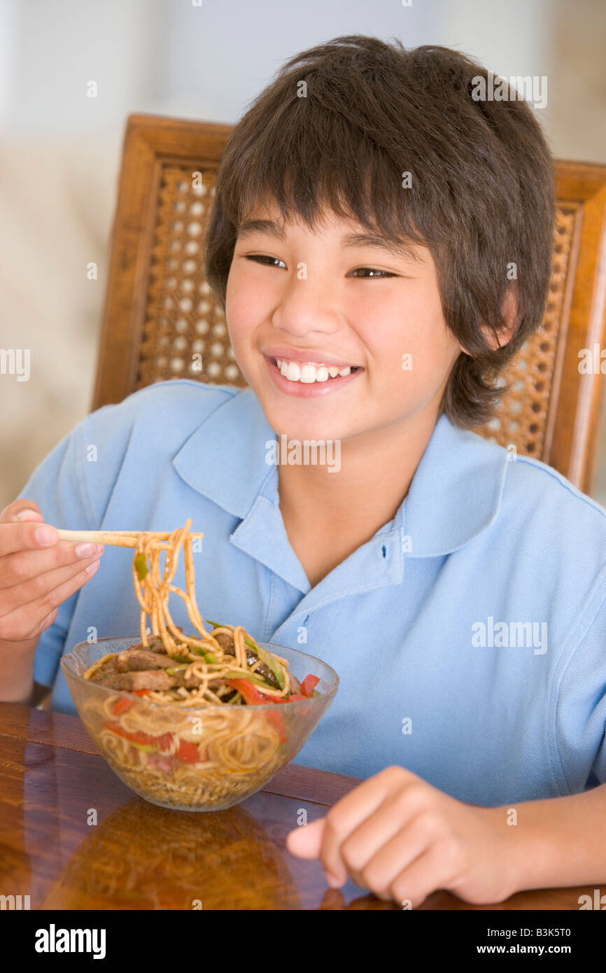 Young boy in dining room eating chinese food smiling Stock Photo - Alamy