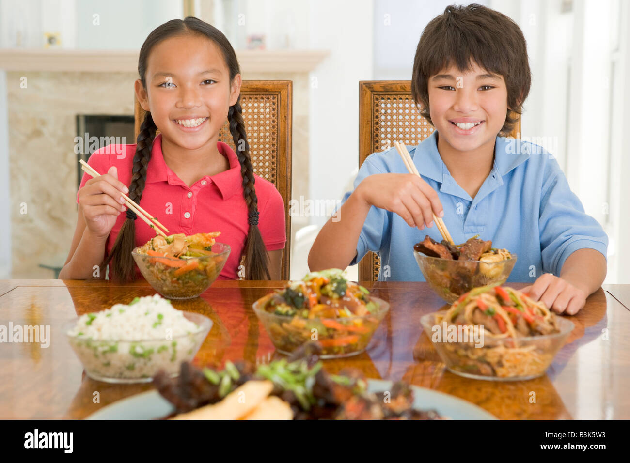 Two young children eating chinese food in dining room smiling Stock ...