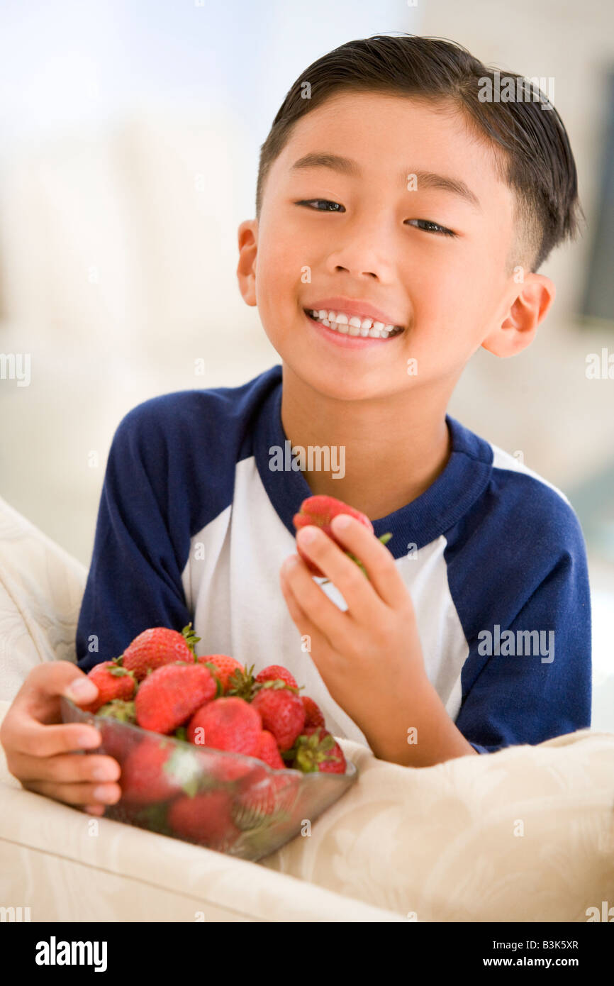 Young boy eating strawberries in living room smiling Stock Photo - Alamy