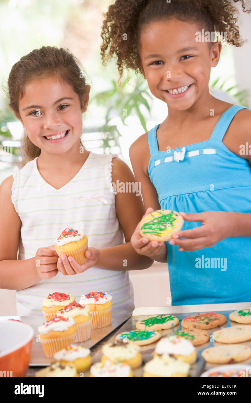 Two children in kitchen decorating cookies smiling Stock Photo - Alamy