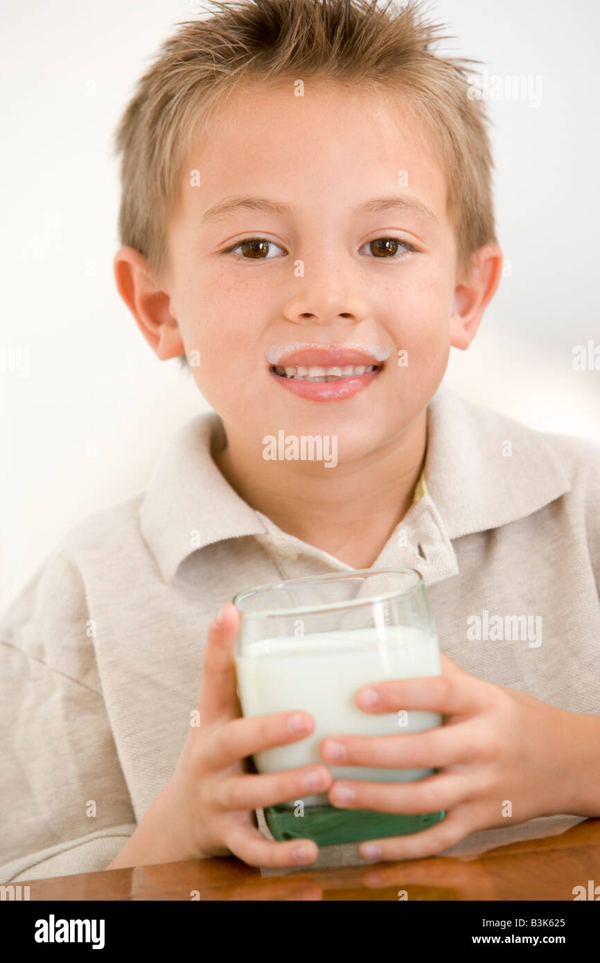 Young boy indoors drinking milk smiling Stock Photo - Alamy