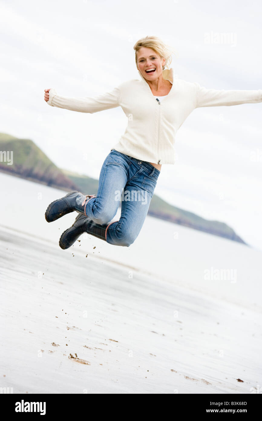 Woman jumping on beach smiling Stock Photo - Alamy