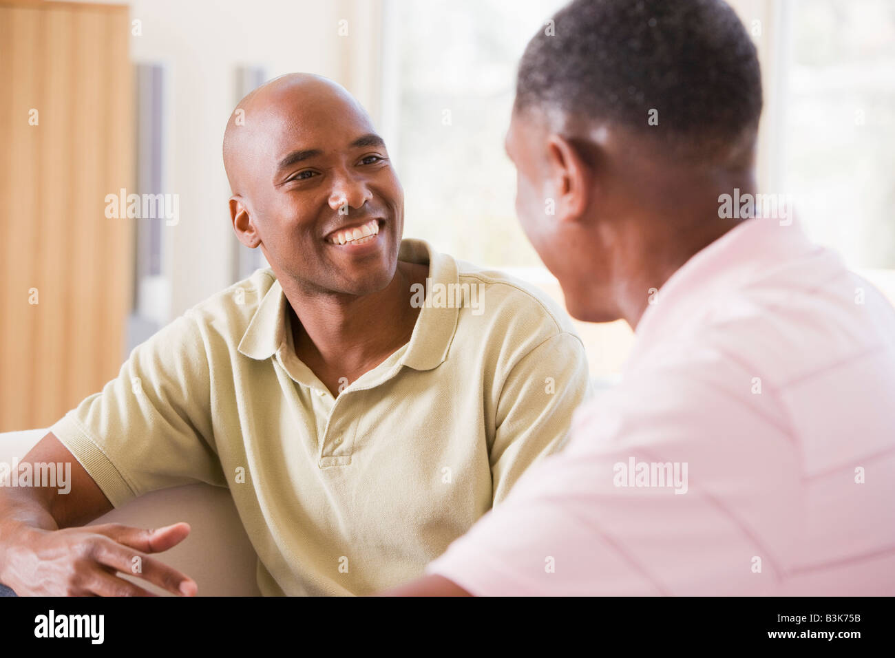 Two men in living room talking and smiling Stock Photo - Alamy