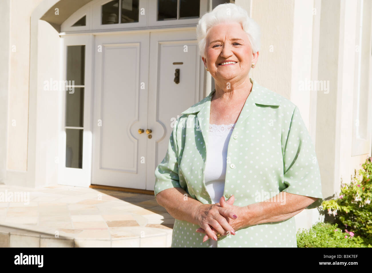 Senior woman standing outside her home Stock Photo - Alamy