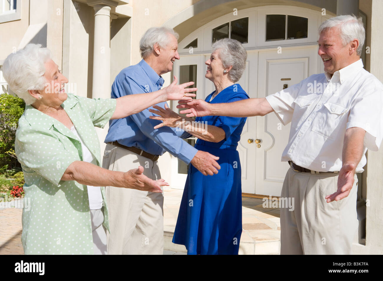 Two senior couples greeting each other with open arms Stock Photo - Alamy