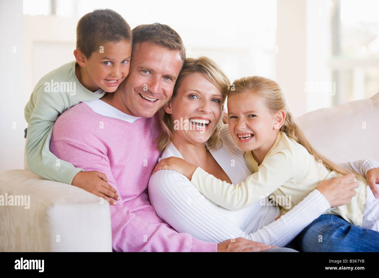 Family sitting in living room smiling Stock Photo - Alamy