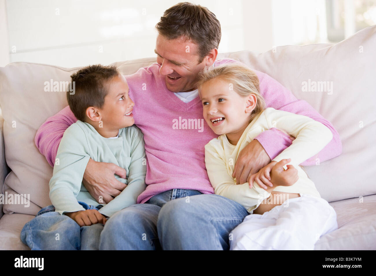Man and two children sitting in living room smiling Stock Photo - Alamy