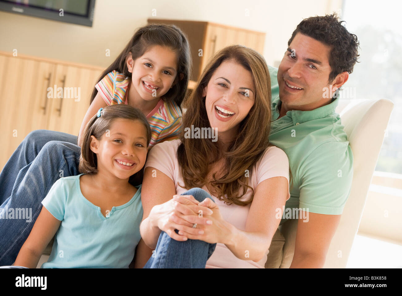 Family sitting in living room smiling Stock Photo - Alamy