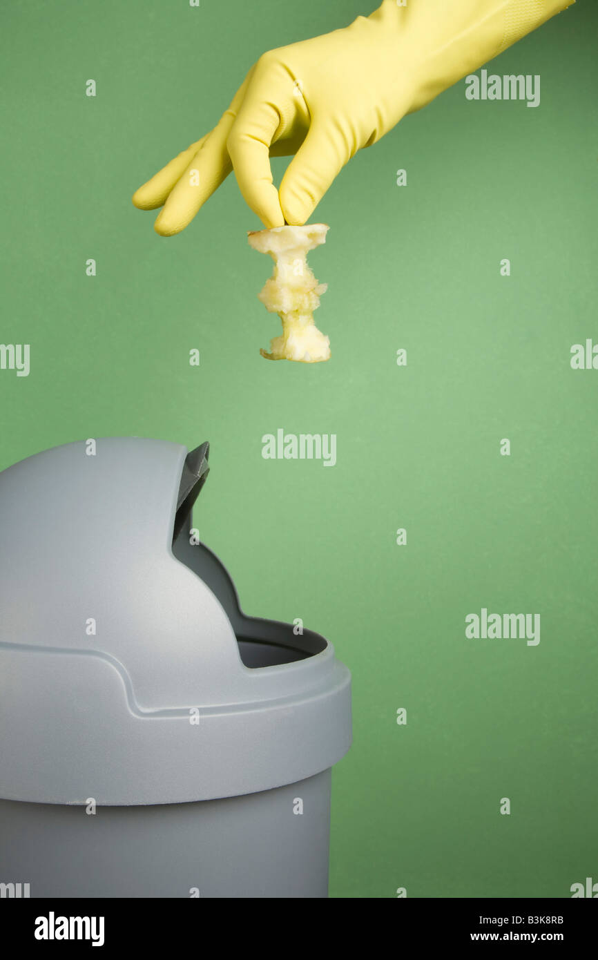 Placing an apple core in to a bin for composting Stock Photo - Alamy