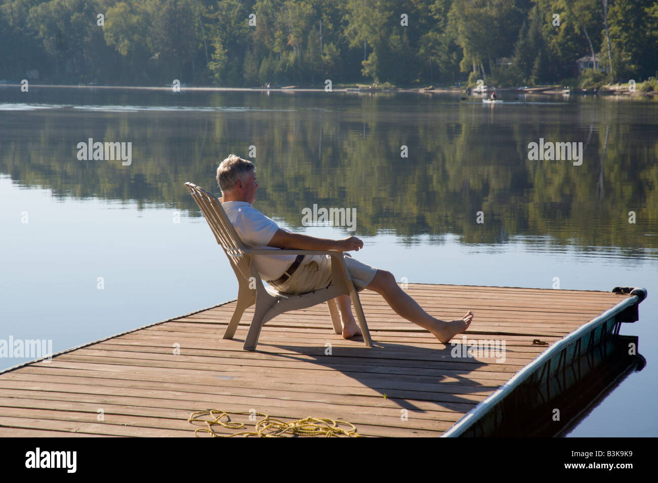 Man sitting on his dock alone in the morning sunrise Stock Photo - Alamy