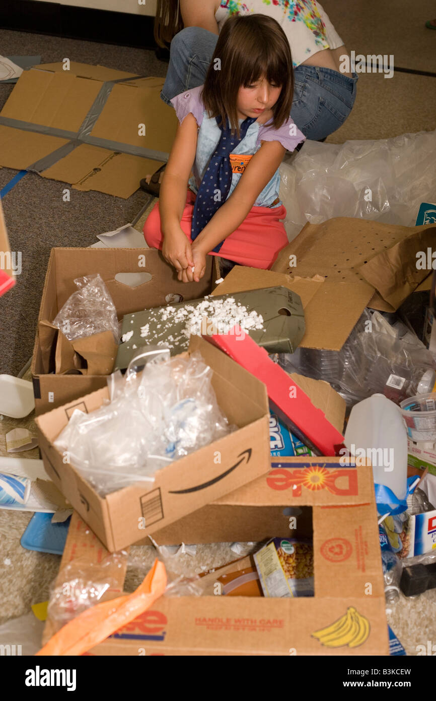 first grade girl making selection from recycled materials of cardboard ...