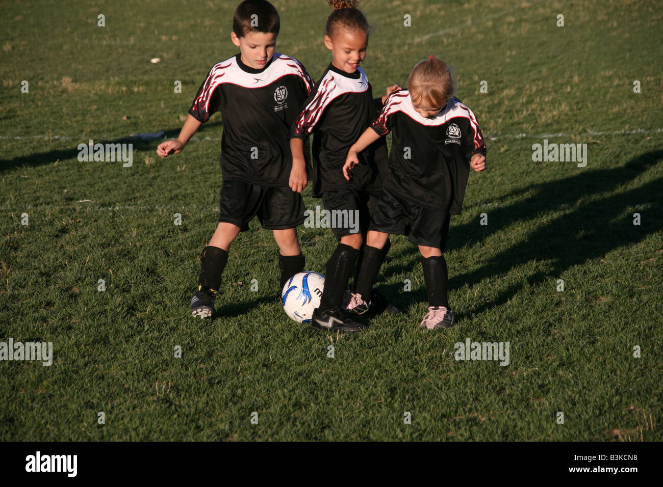 Three young children playing soccer game Stock Photo - Alamy