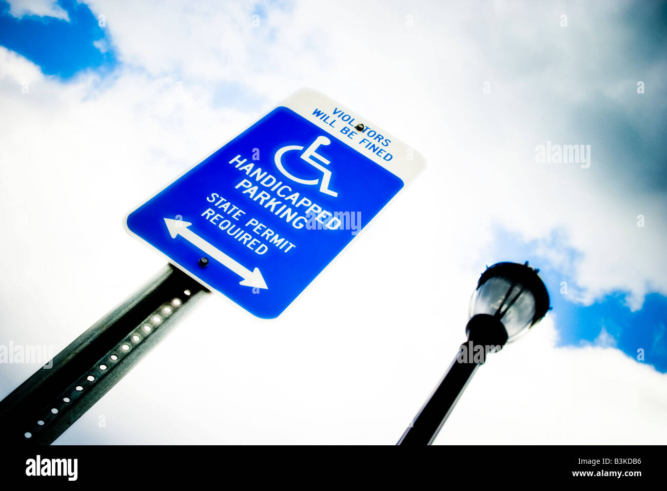 Traffic sign on a metal pole next to a lamppost reading HANDICAPPED ...