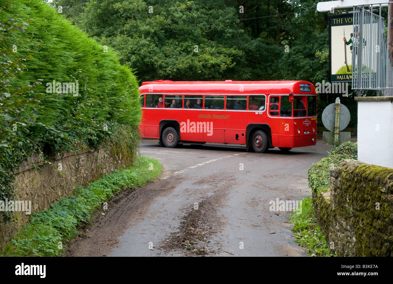 Old fashioned red English bus driving through the countryside in Surrey ...