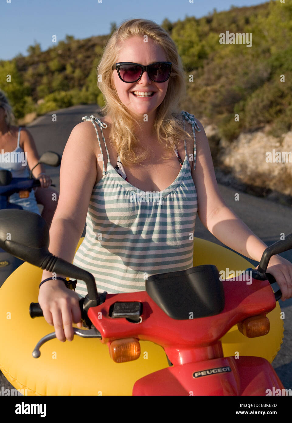 Woman wearing inflatable ring sitting on scooter, Spetses, Greece Stock ...