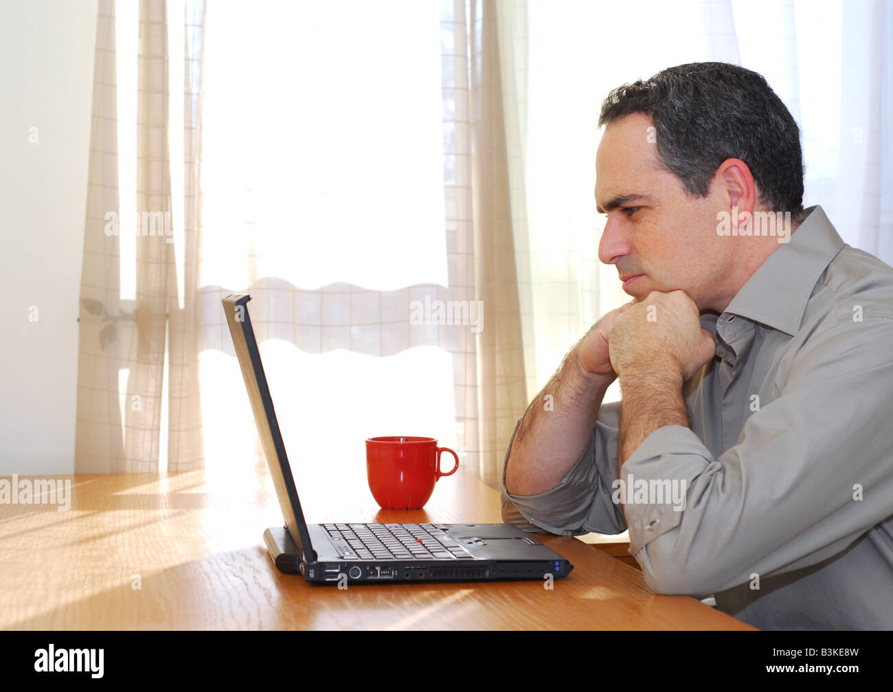Man sitting at his desk with a laptop looking concerned Stock Photo - Alamy