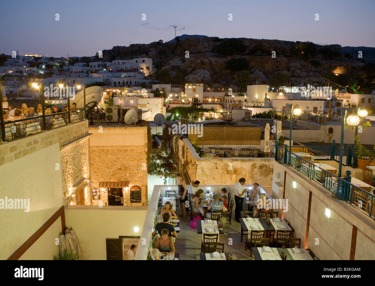 People in rooftop taverna at dusk, Lindos, Rhodes, Greece Stock Photo ...