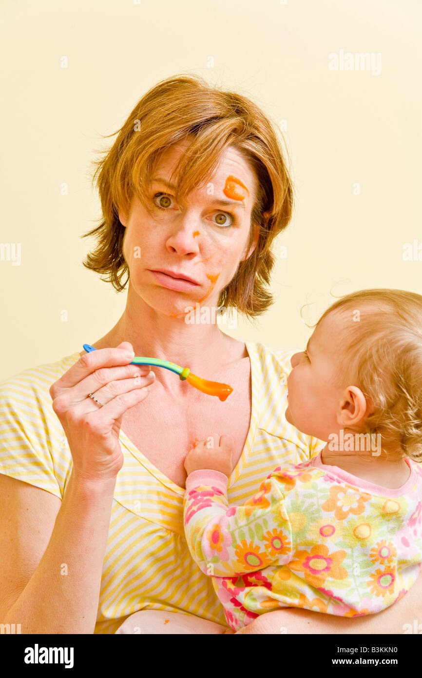 Frustrated mother trying to feed messy baby Stock Photo - Alamy